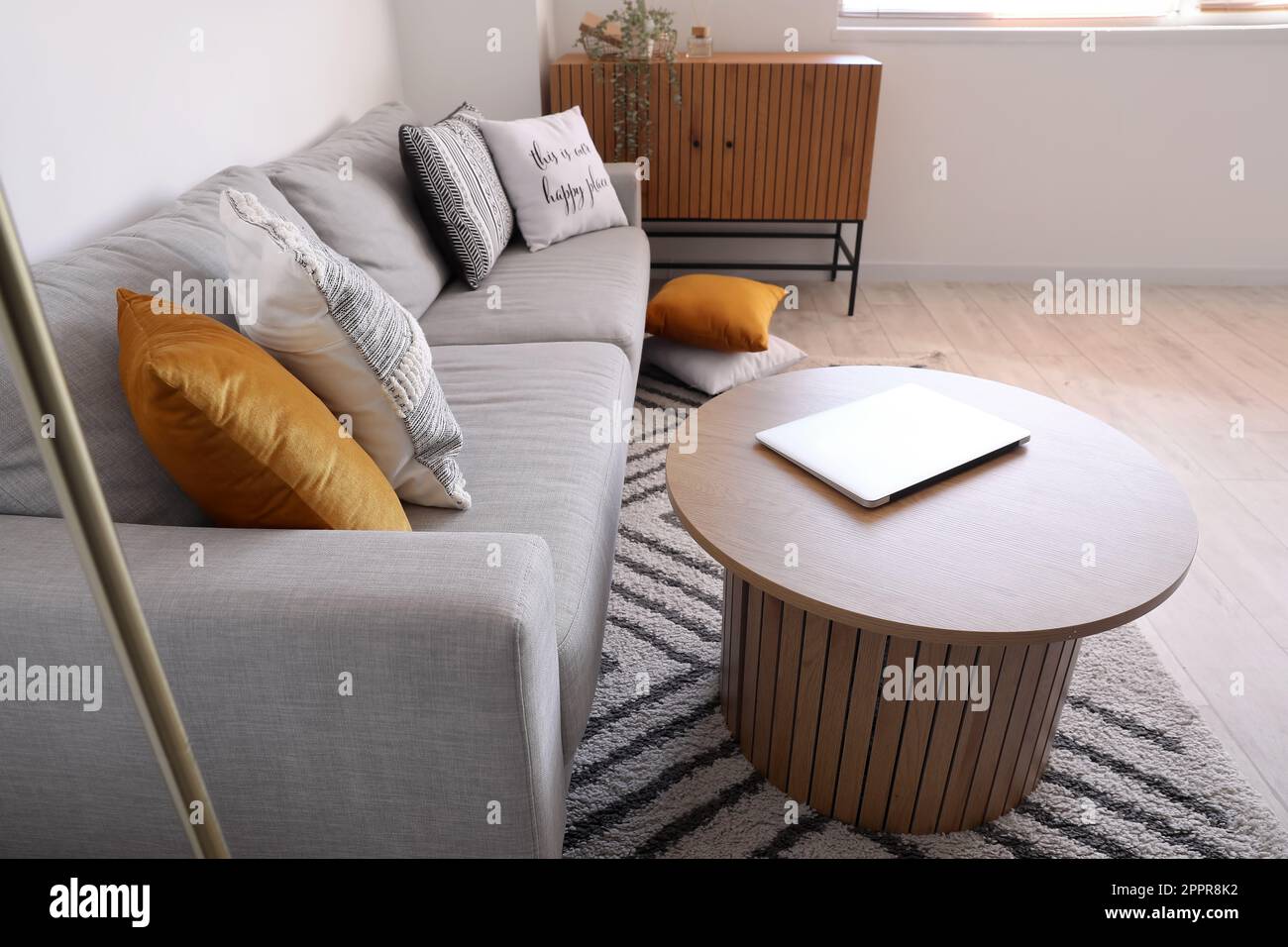 Modern laptop on coffee table near grey sofa in stylish living room ...