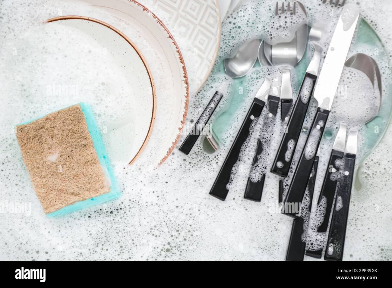 Cleaning sponge with dishes and foam in water, closeup Stock Photo - Alamy