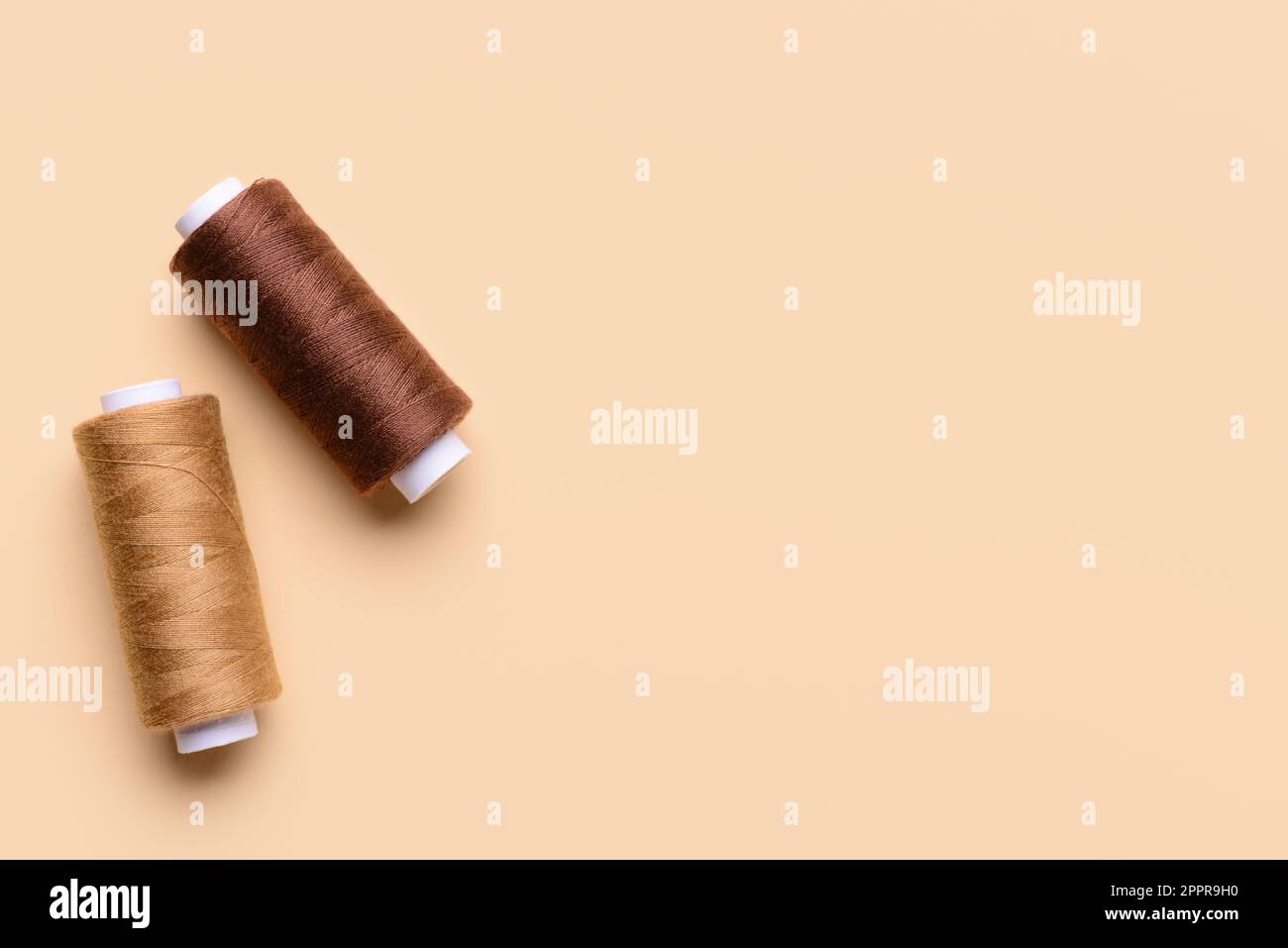 Two thread spools on color background Stock Photo - Alamy