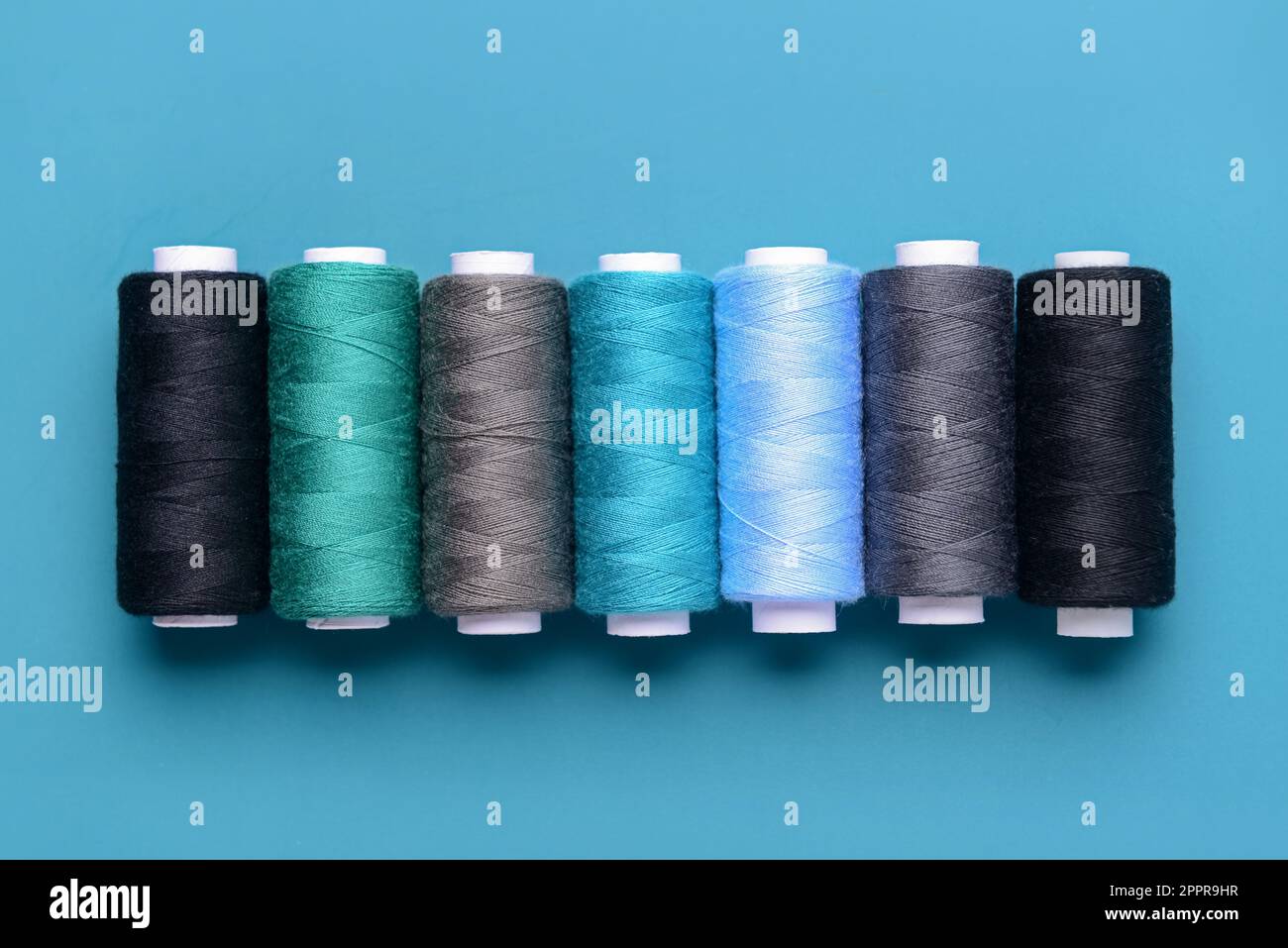 Set of different thread spools on blue background Stock Photo - Alamy