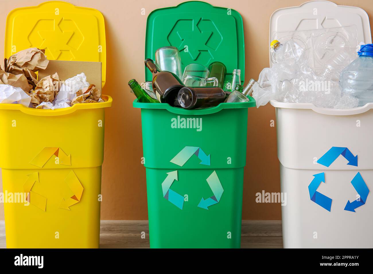 Trash bins with recycling symbol and different garbage near beige wall ...