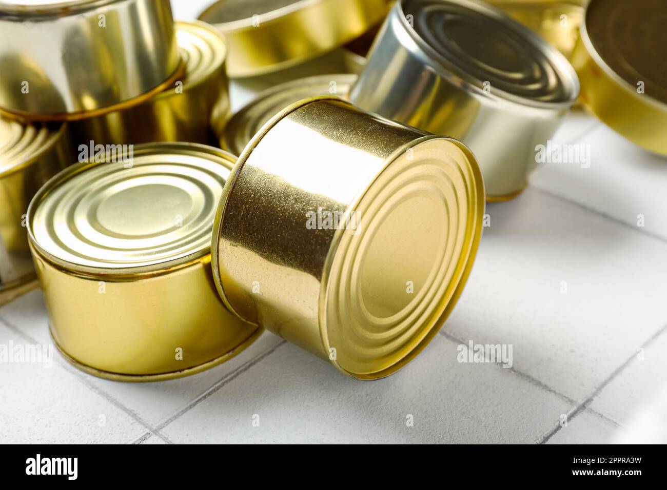Different tin cans with fish on tiled table Stock Photo - Alamy