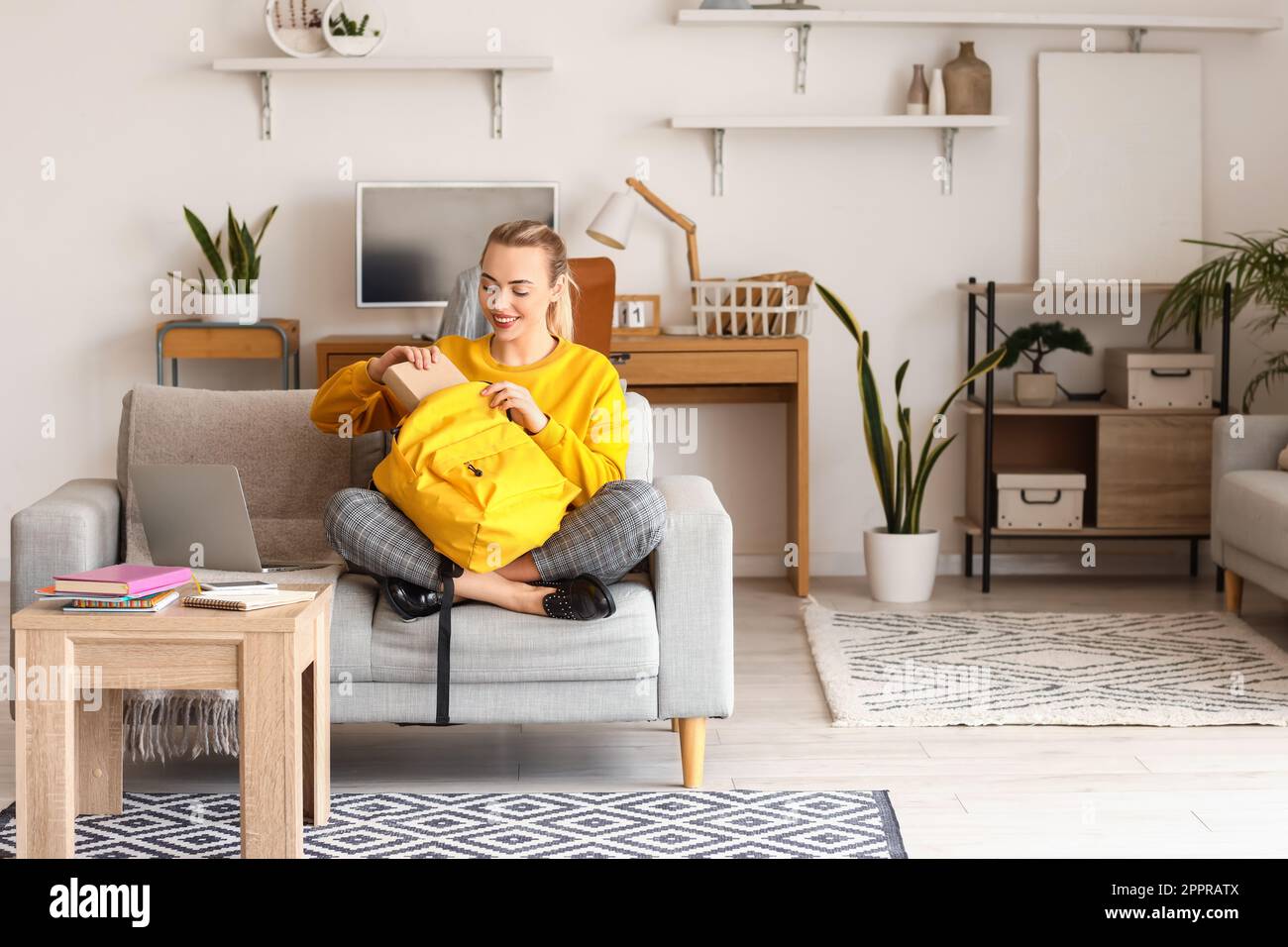 Female student taking book from backpack at home Stock Photo - Alamy