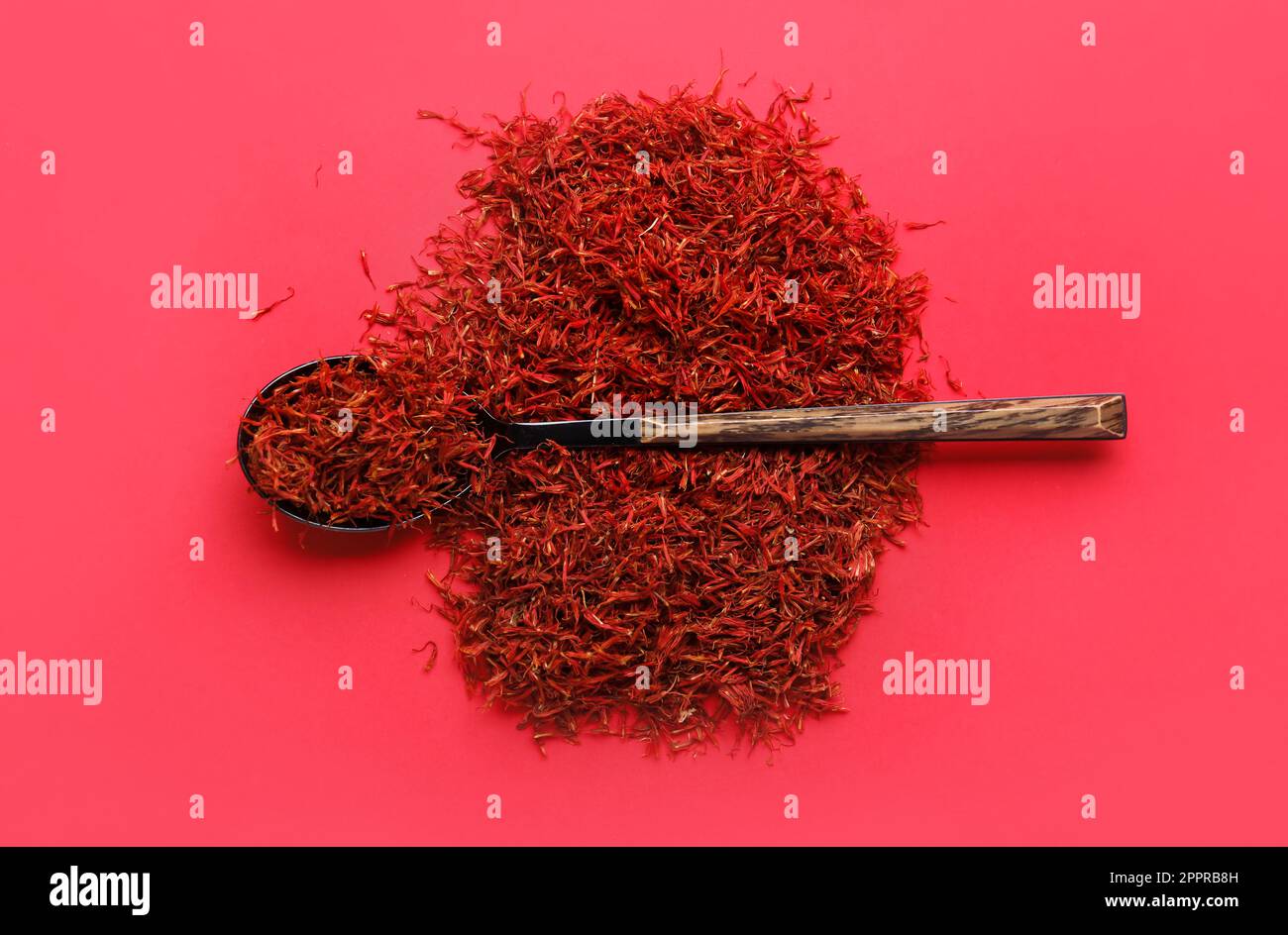 Spoon with pile of saffron on red background Stock Photo - Alamy