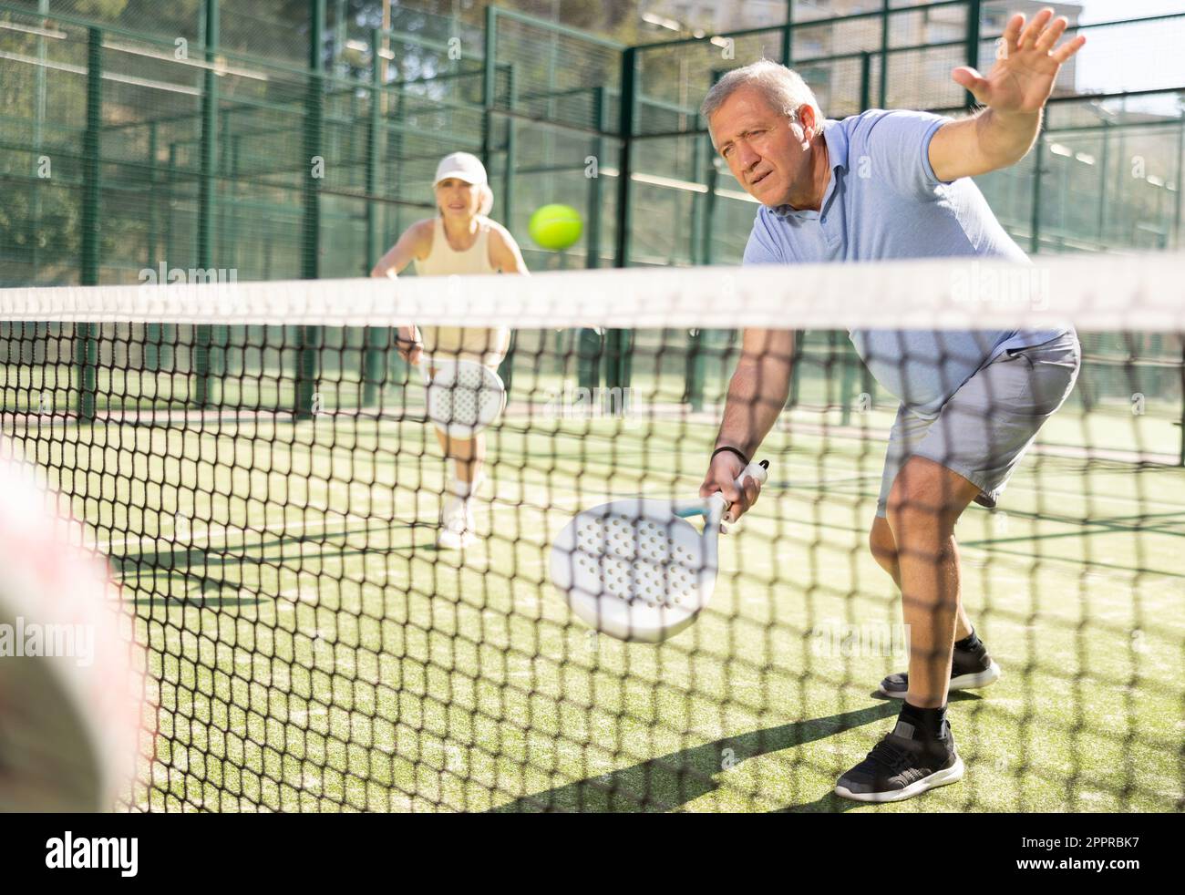 Motivated senior man playing padel with his teammate in court Stock ...
