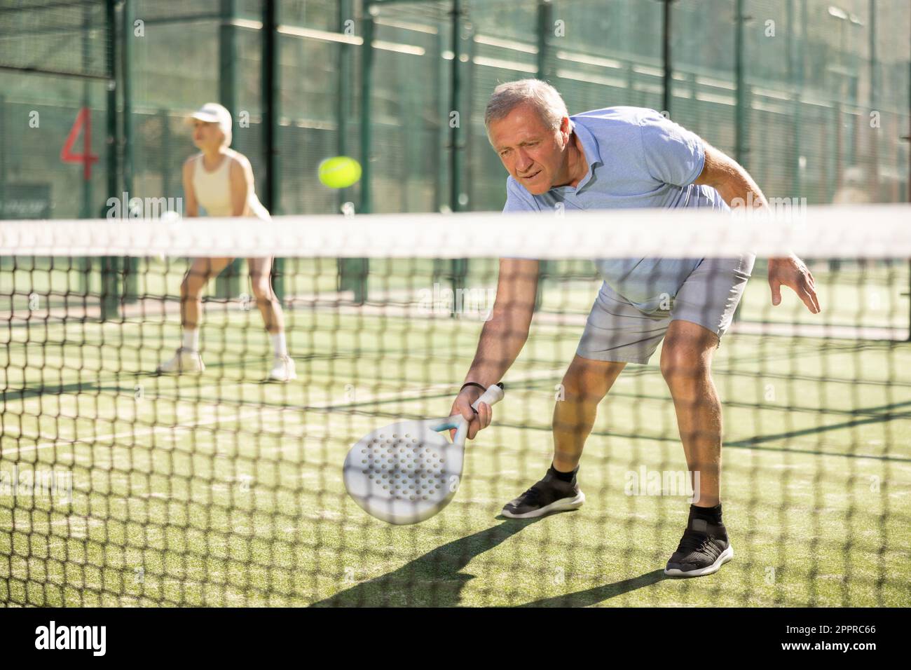 Old man playing Padel Tennis in open-air tennis court Stock Photo - Alamy