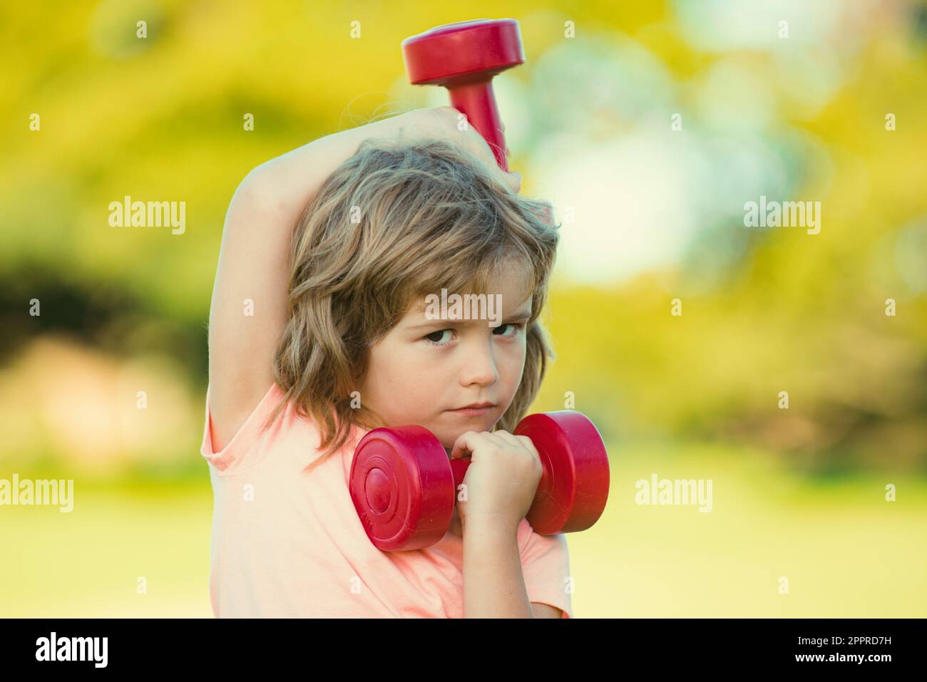 Sport child boy with strong biceps muscles. Kids exercising fitness dumbbells. Strong little boy ...