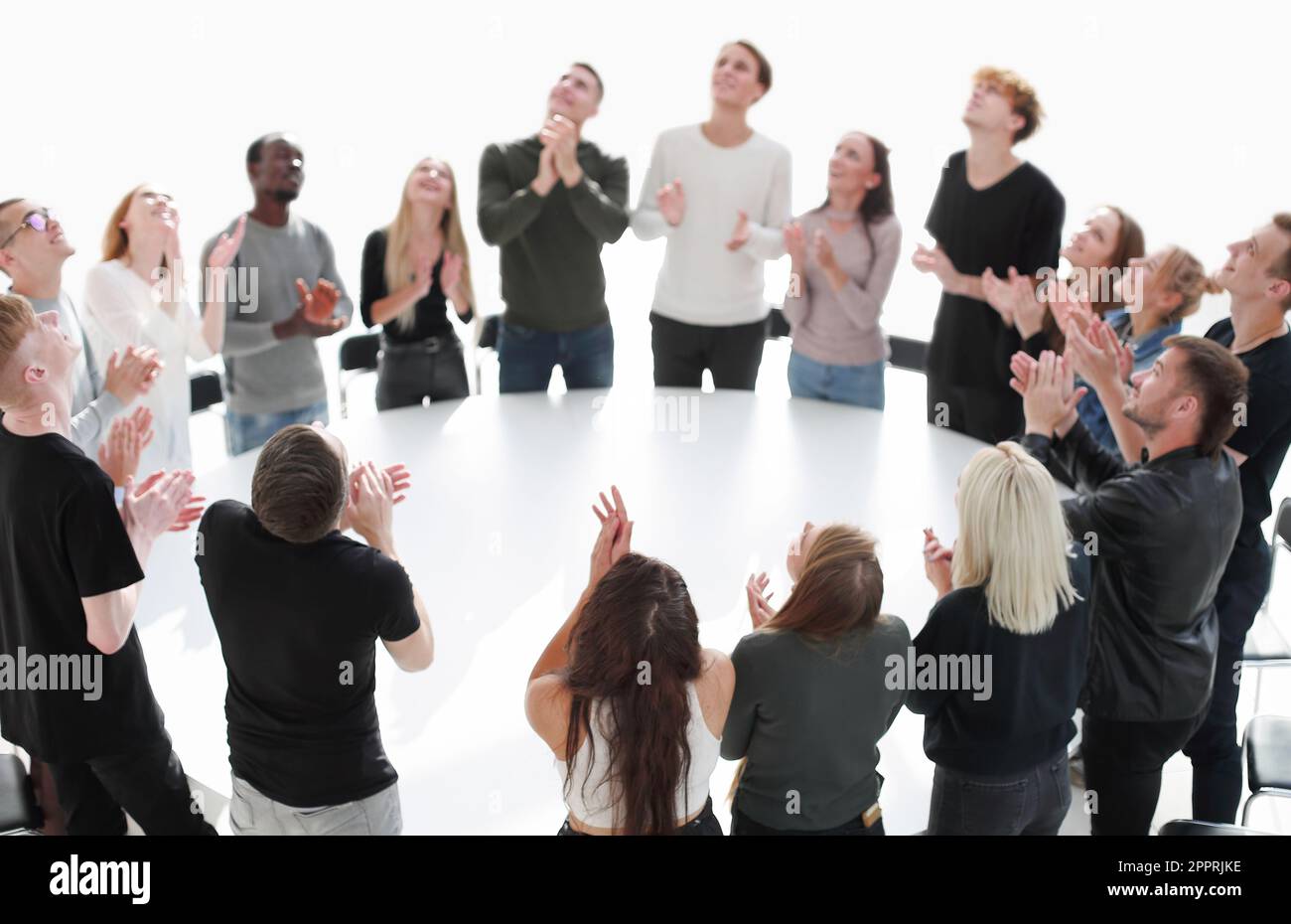 group of diverse young people standing around a round table Stock Photo ...