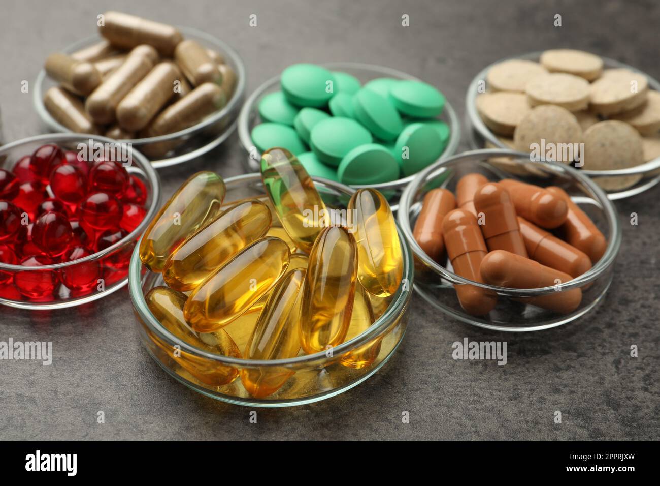 Different dietary supplements in glass bowls on grey table Stock Photo ...