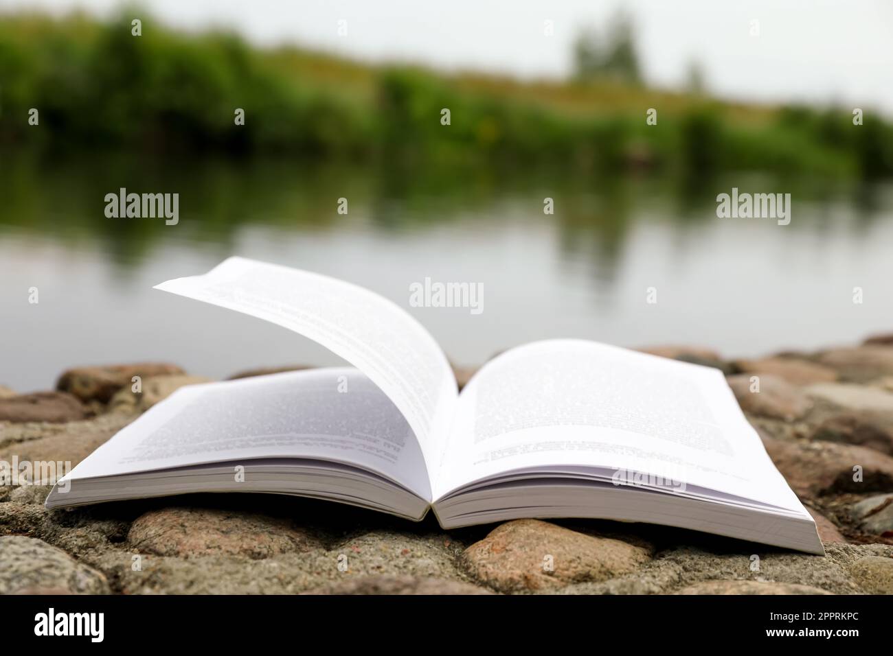 Open book on rocky shore near river Stock Photo - Alamy