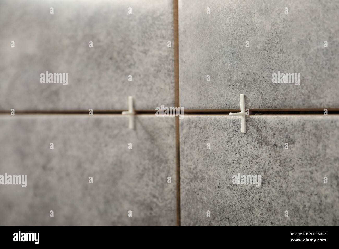 Stylish tiles with spacers on wall in room Stock Photo - Alamy