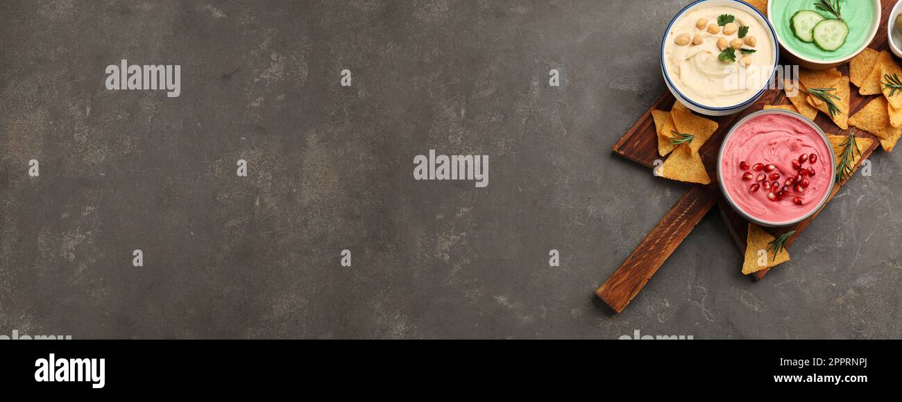 Different delicious hummuses and tortilla chips on grey table, top view ...