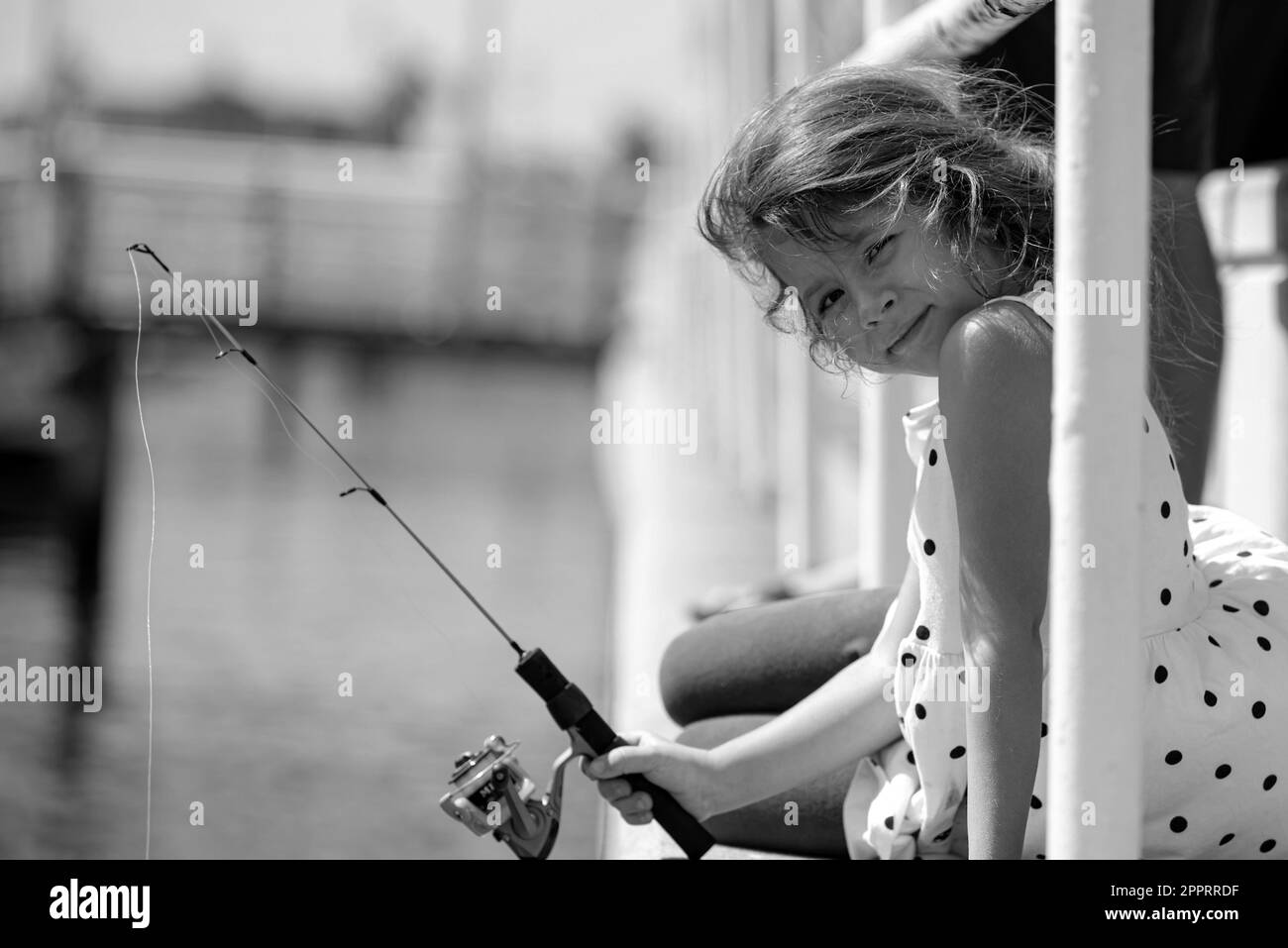 Funny little child girl catch a fish by a fishing rod Stock Photo - Alamy
