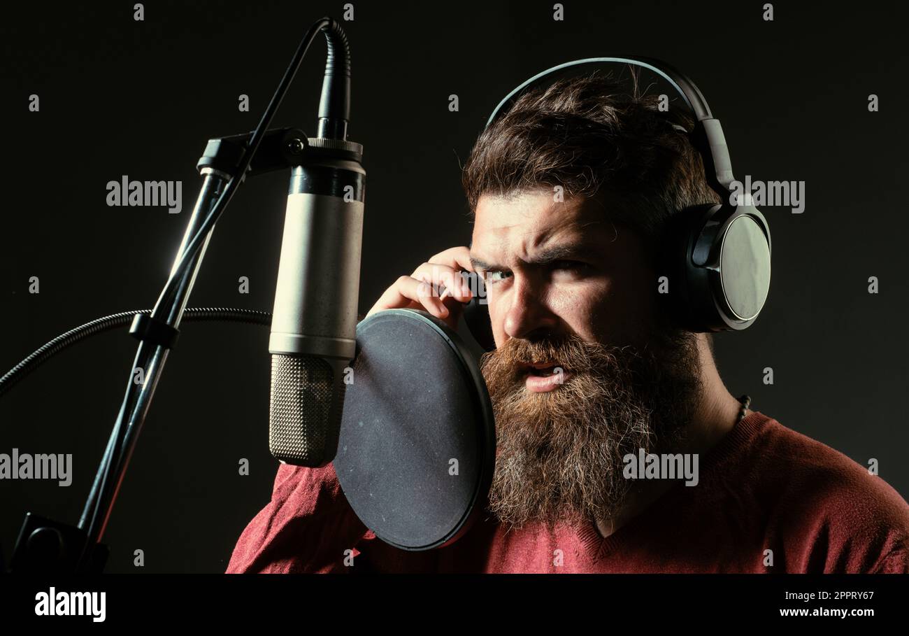 Portrait of singer wearing headphones is performing a song with a ...