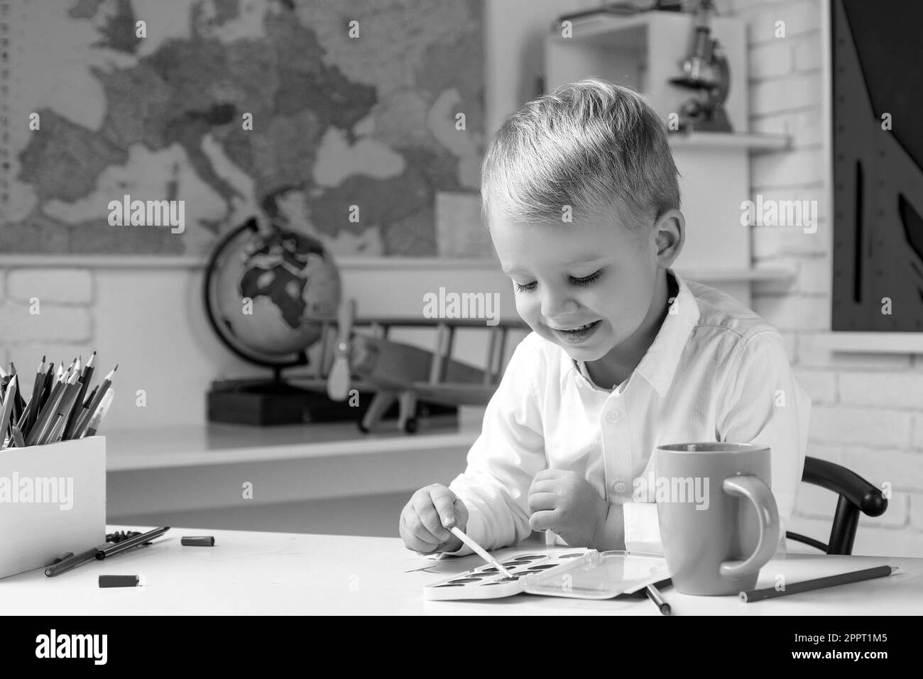 Pupil child is sitting at a desk indoors. Cute pupil with funny face ...