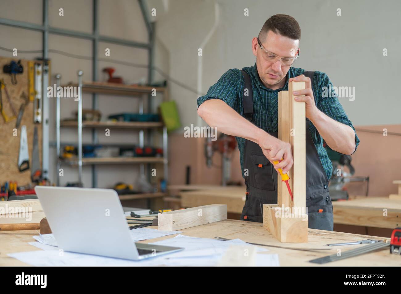Caucasian man assembling a table with a screwdriver Stock Photo - Alamy