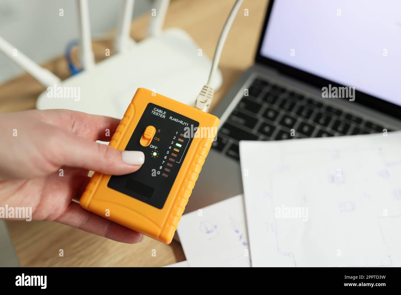 Woman holds LAN speed tester near Wi-Fi router and laptop Stock Photo ...
