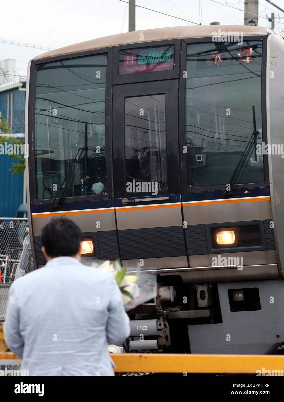 A man mourns for victims while a train is passing near the site of the derailment accident in ...