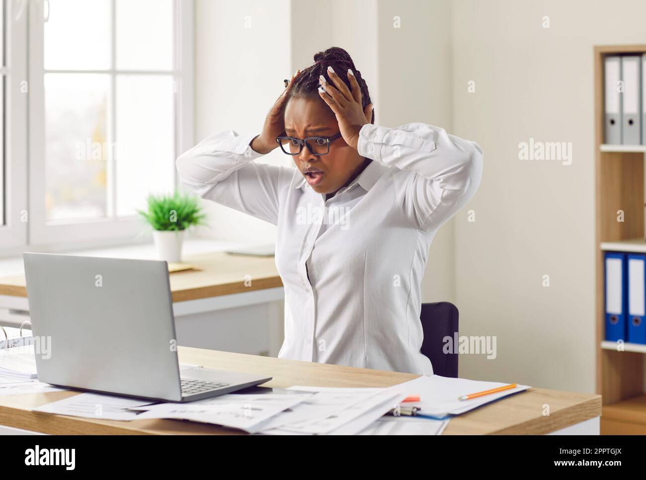 Stressed young woman clutching her head in panic Stock Photo - Alamy