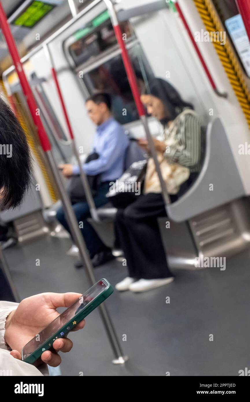 Passengers using mobile phones on the Hong Kong MTR subway, Hong Kong ...