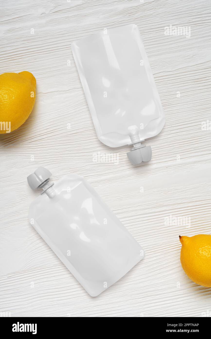 White empty plastic pouches for baby food, fruit puree on wood table ...