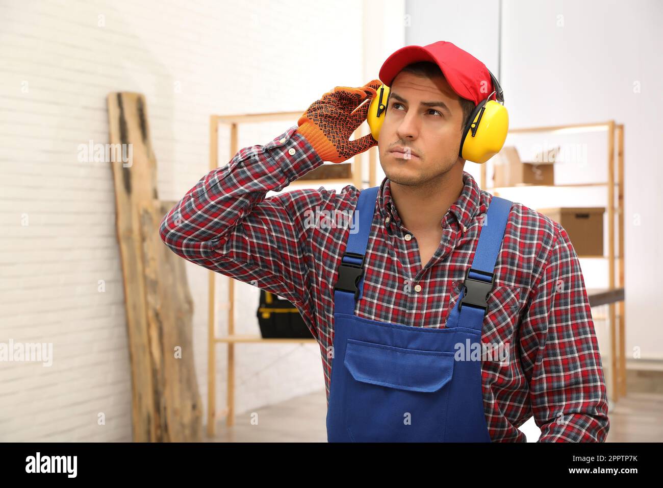 Worker wearing safety headphones indoors. Hearing protection device ...