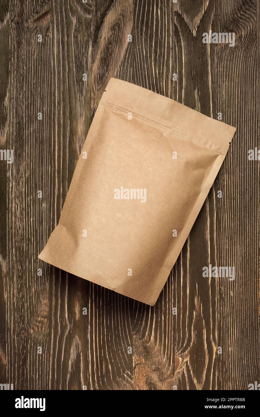 Brown kraft paper pouch bag on wood table. Mock-up template for design ...