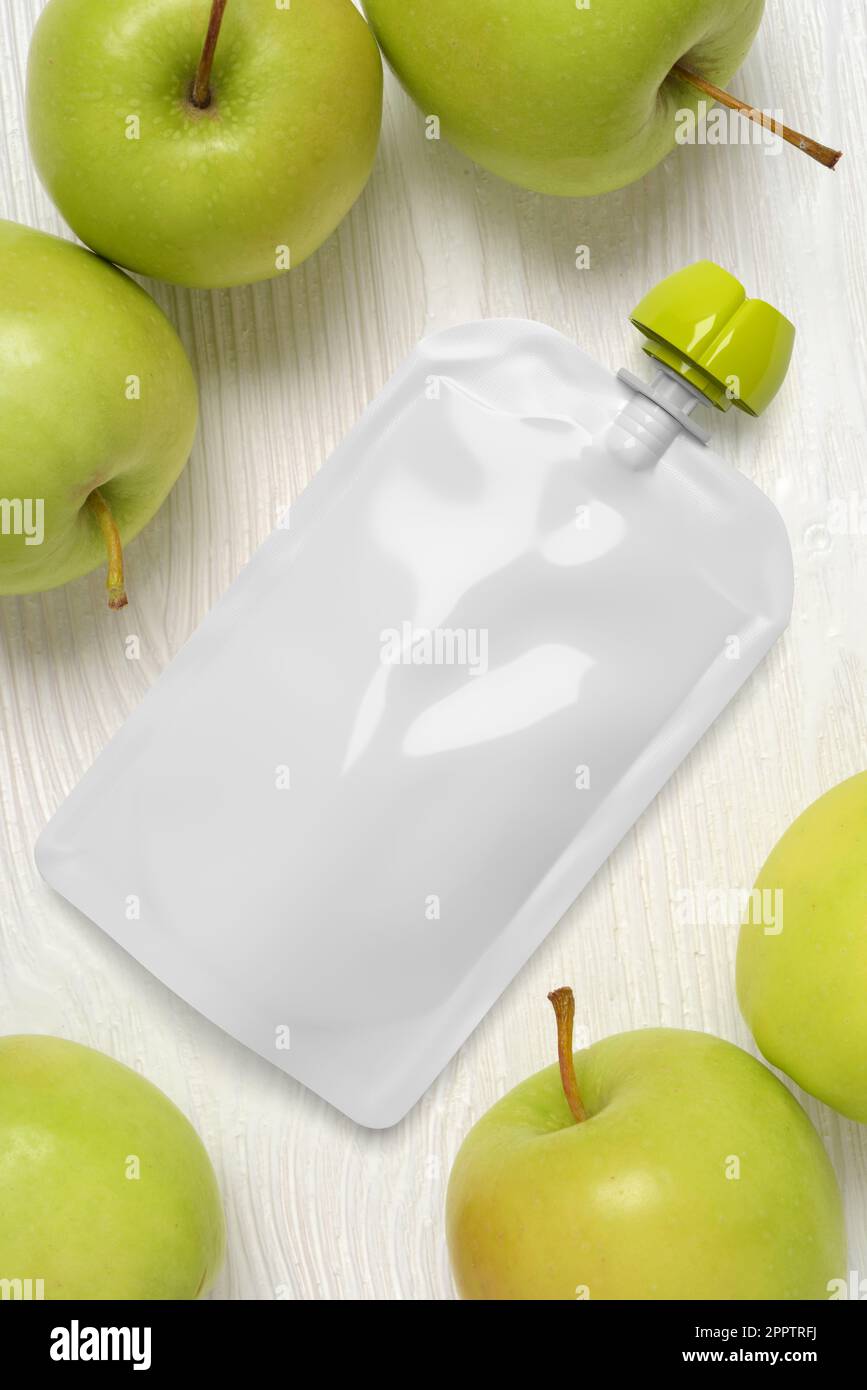 White empty plastic pouche for baby food with green apples on wood ...
