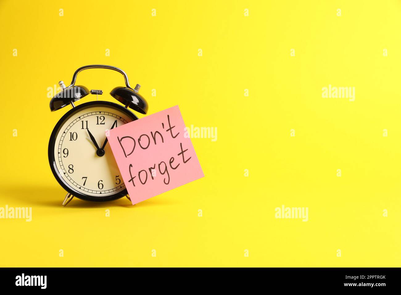 Alarm clock and reminder note with phrase Don't forget on yellow ...
