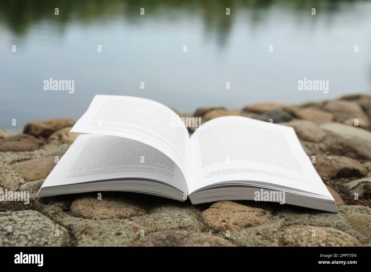 Open book on rocky shore near river Stock Photo - Alamy