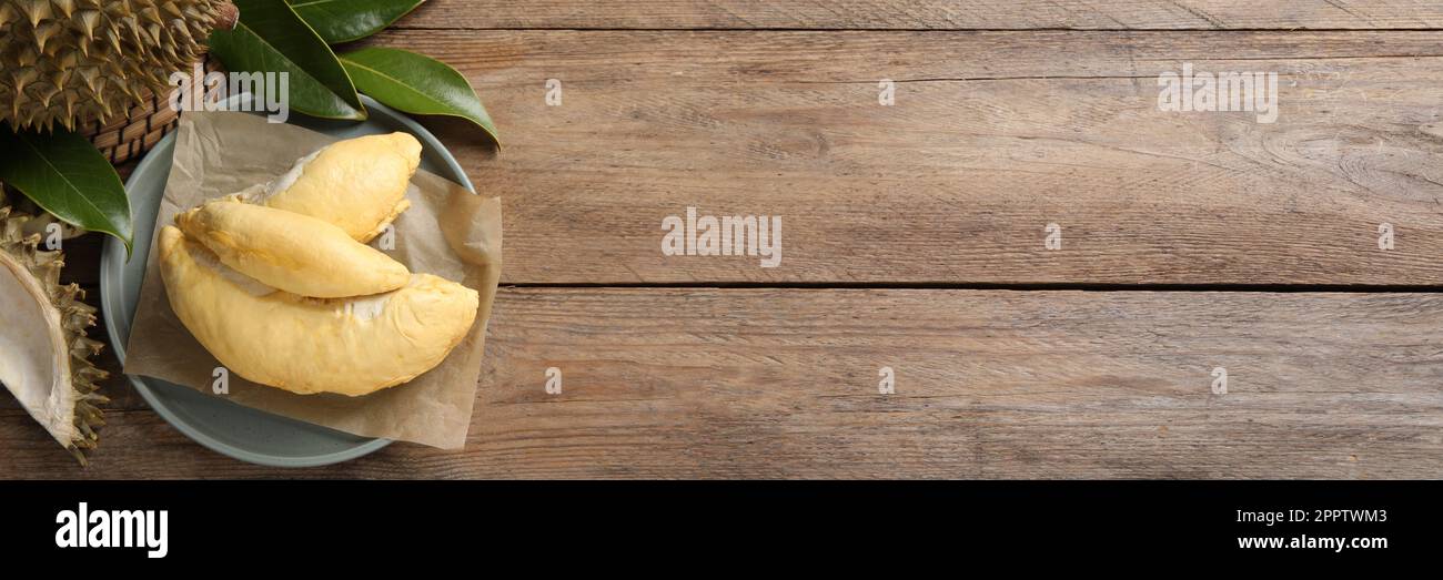 Fresh ripe durians and leaves on wooden table, flat lay with space for ...