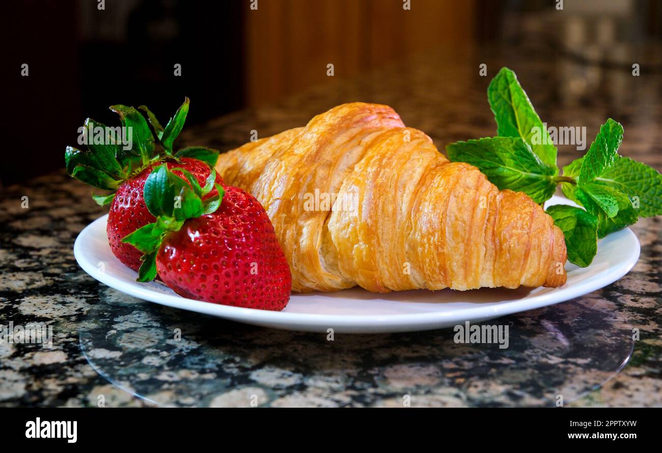 on a plate two delicious appetizing fresh croissants with strawberries ...