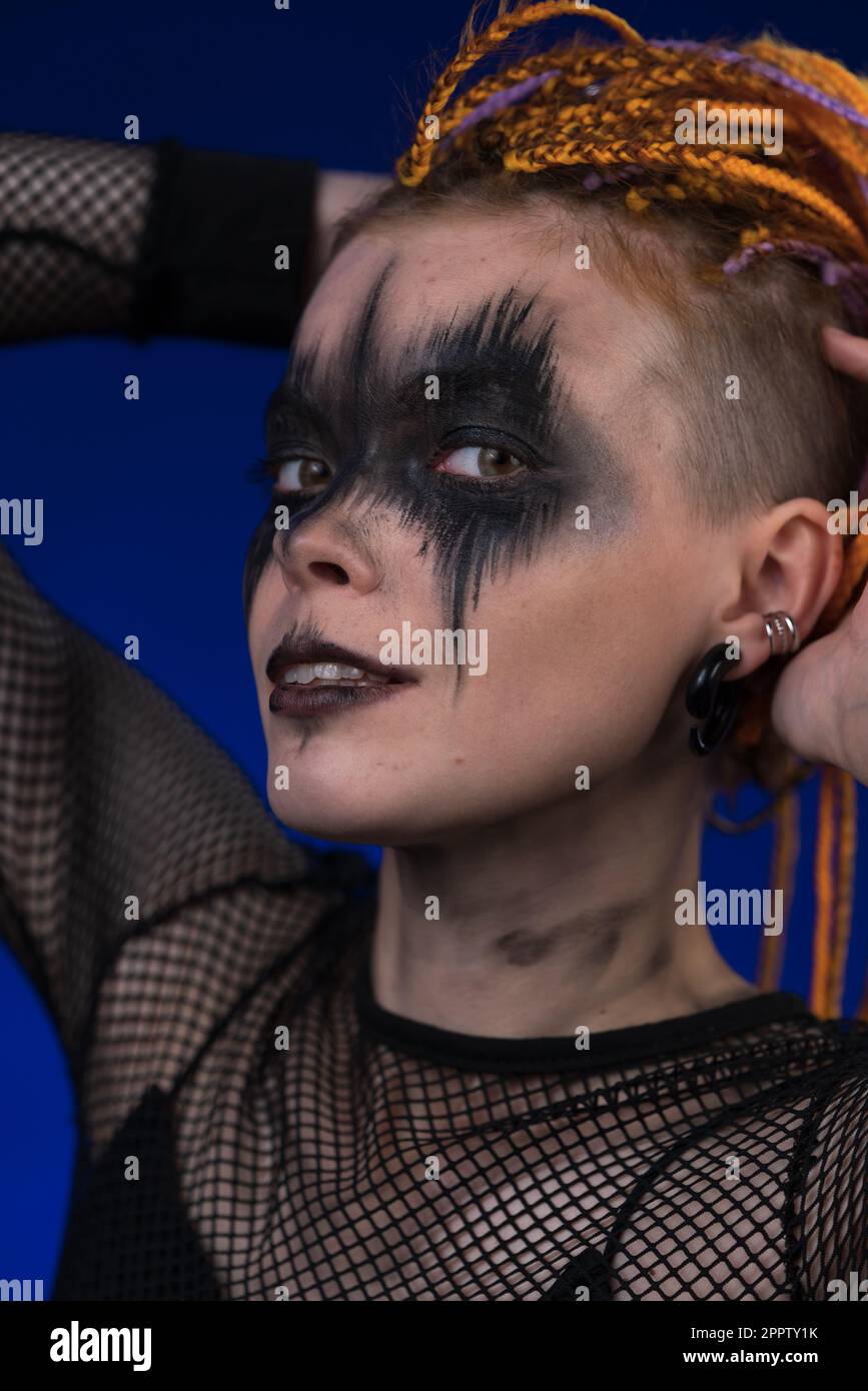 Headshot of young woman with horror black stage make up painted on face ...