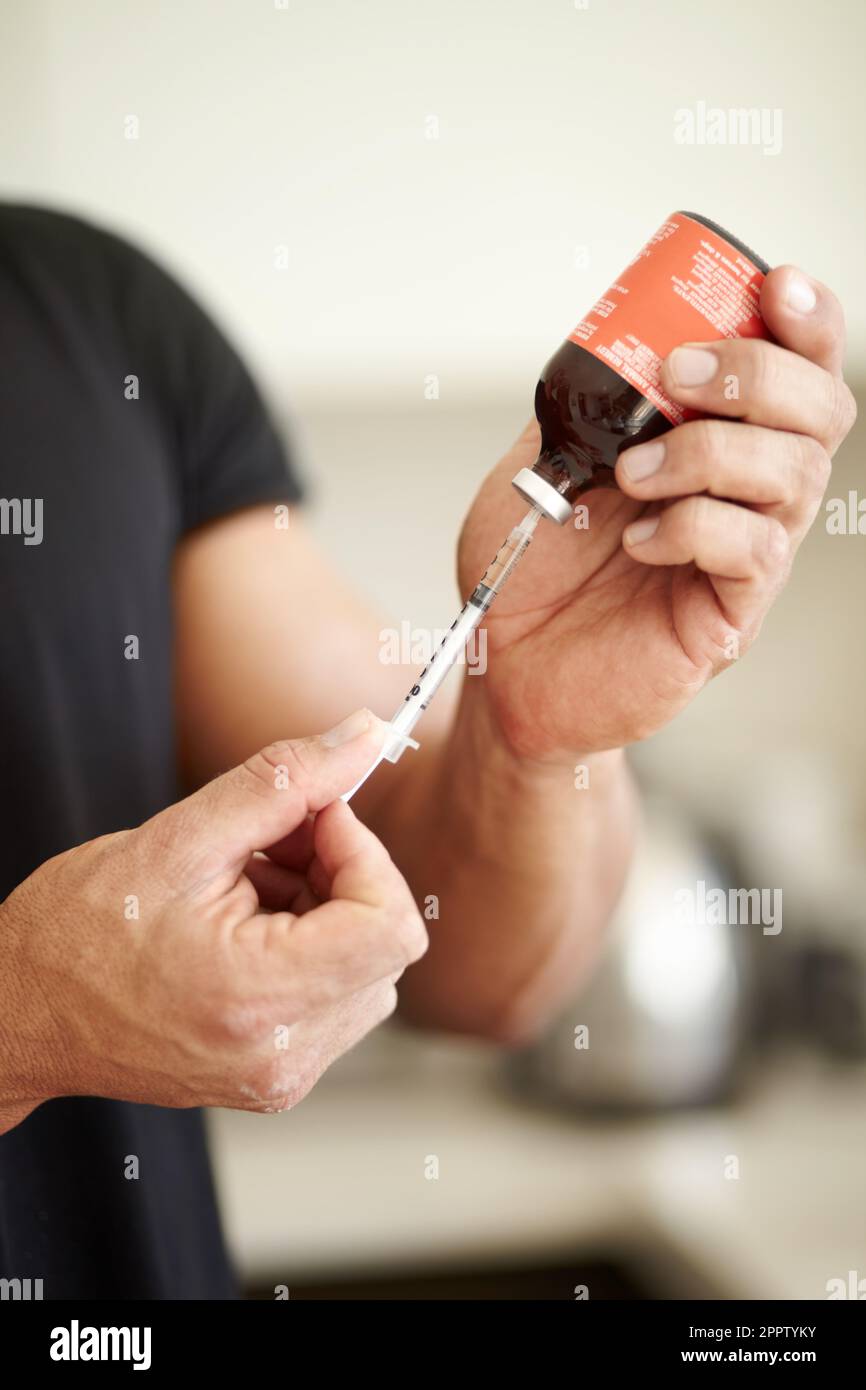 Man, filling a syringe or liquid injection of testosterone and bottle ...