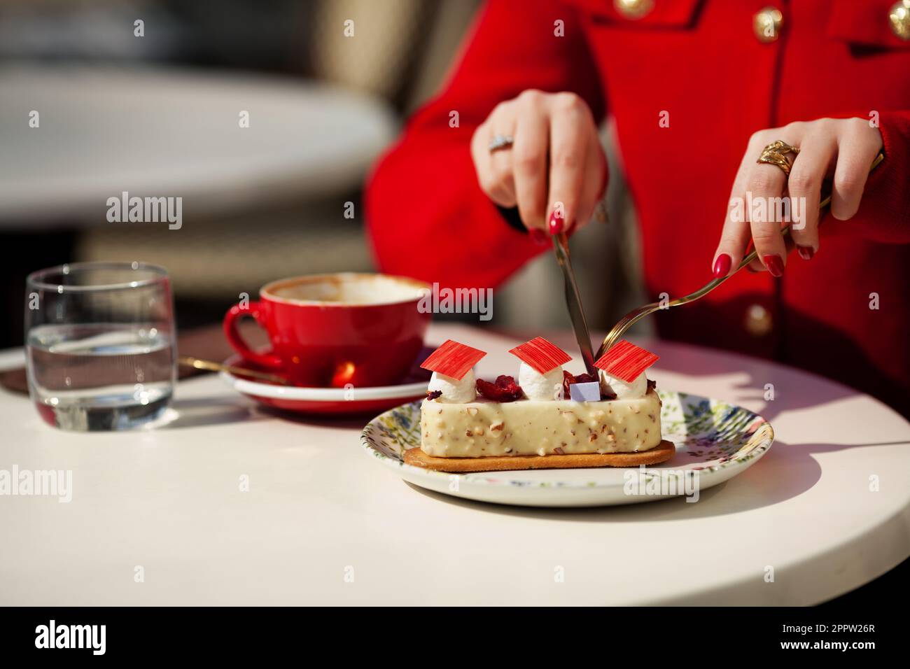 Woman in red clothes eating cake and drinking coffee in cafe. Close up ...