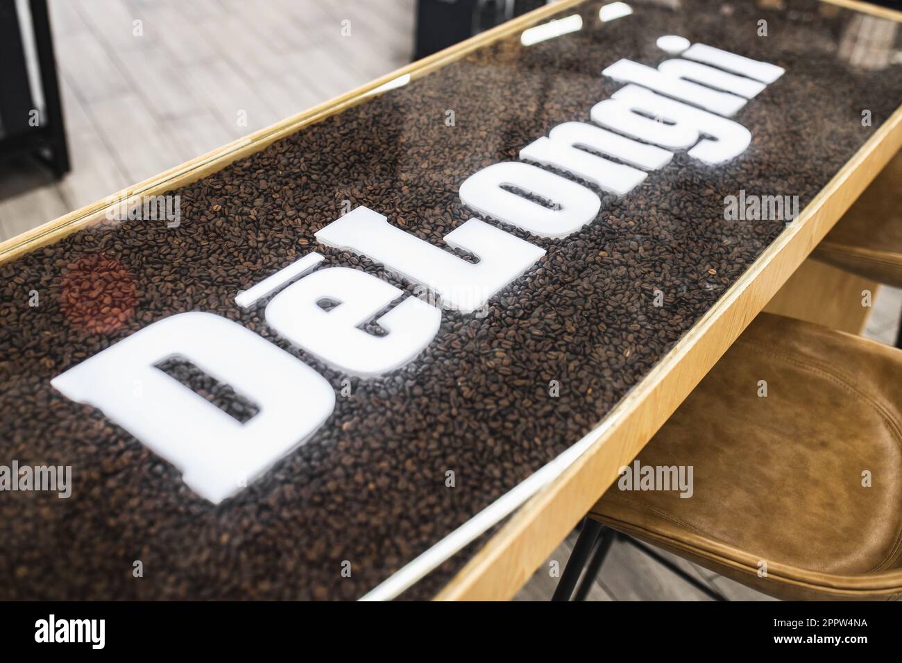 DeLonghi logo on a table with real coffee beans under glass in a coffee ...