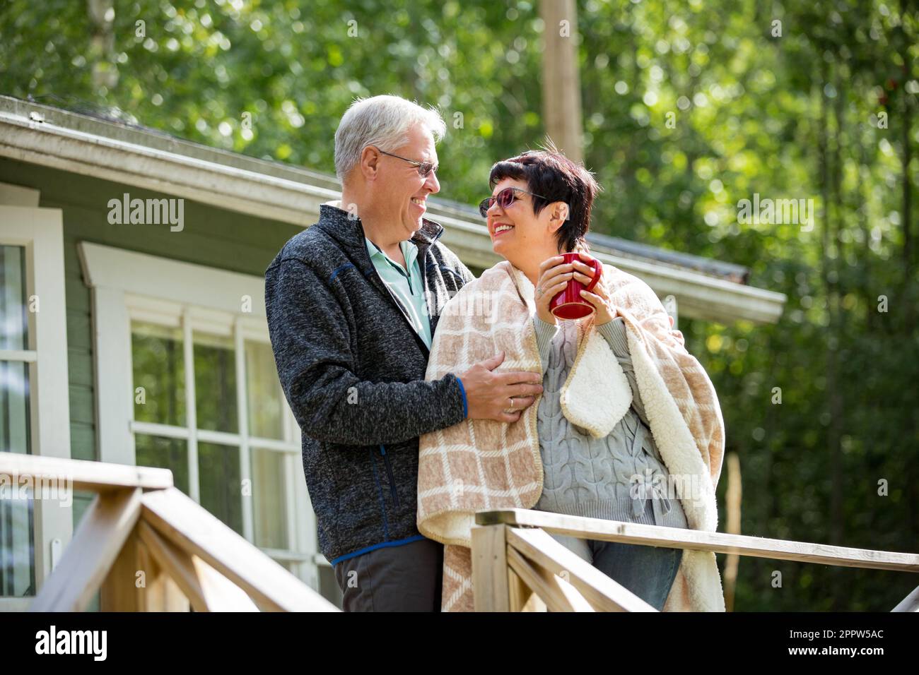 Mature Couple Standing On Porch And Drinking Hot Coffee From Mug They