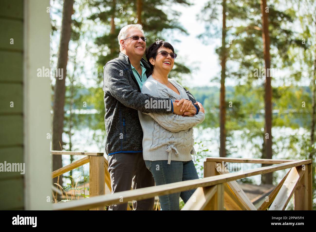 Mature Couple Standing On Porch And Hugging They Are Smiling And