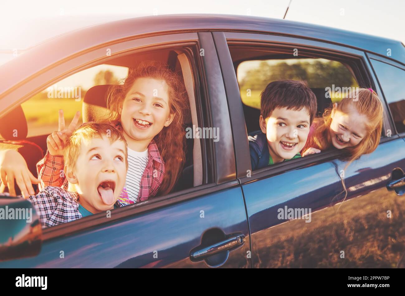 Group of cute children sitting in the car and and looking out through ...