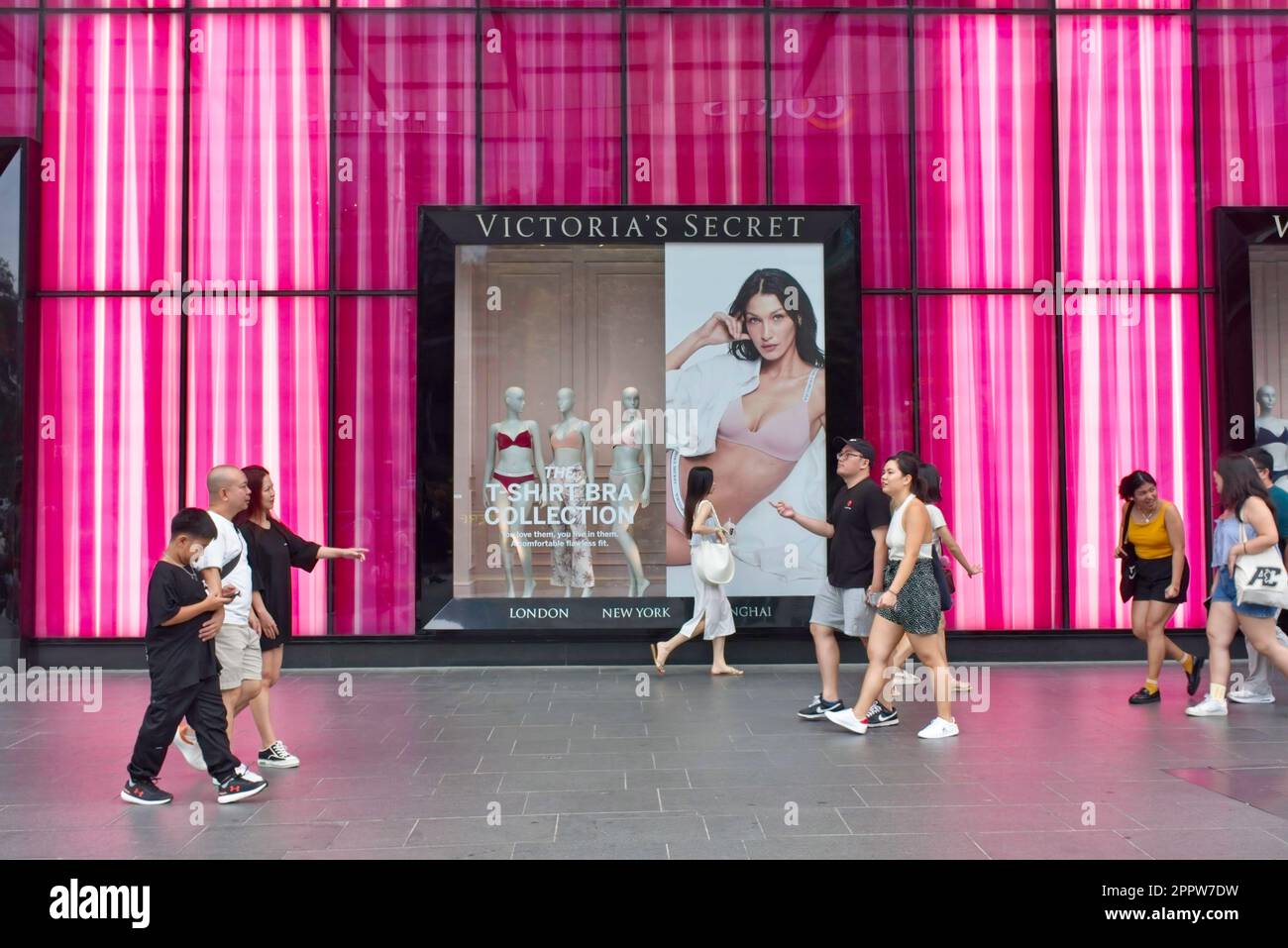 Shoppers are passing in front of a pink-themed Victoria's Secret outlet ...
