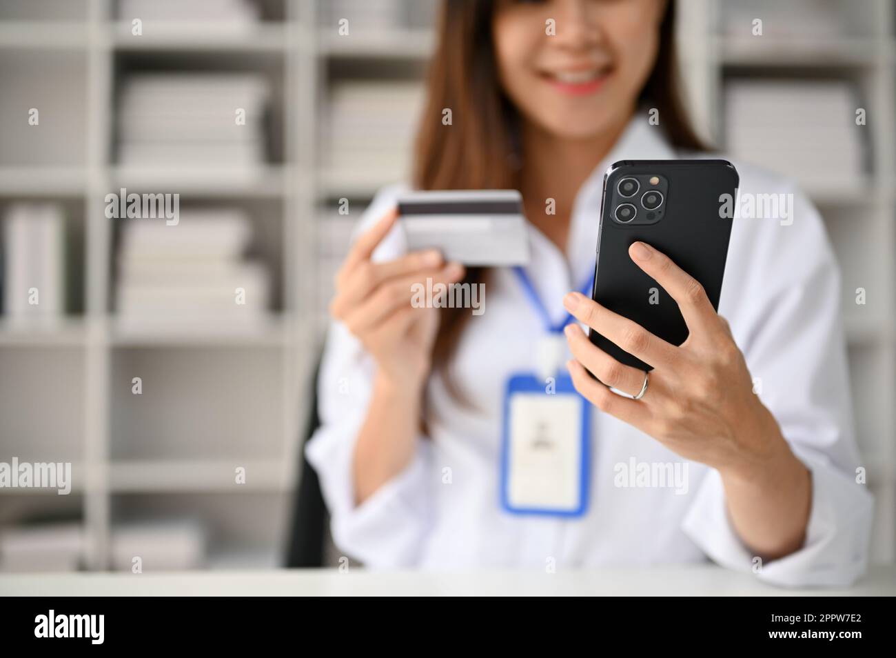 Close-up image of a happy young office employee using a mobile banking ...