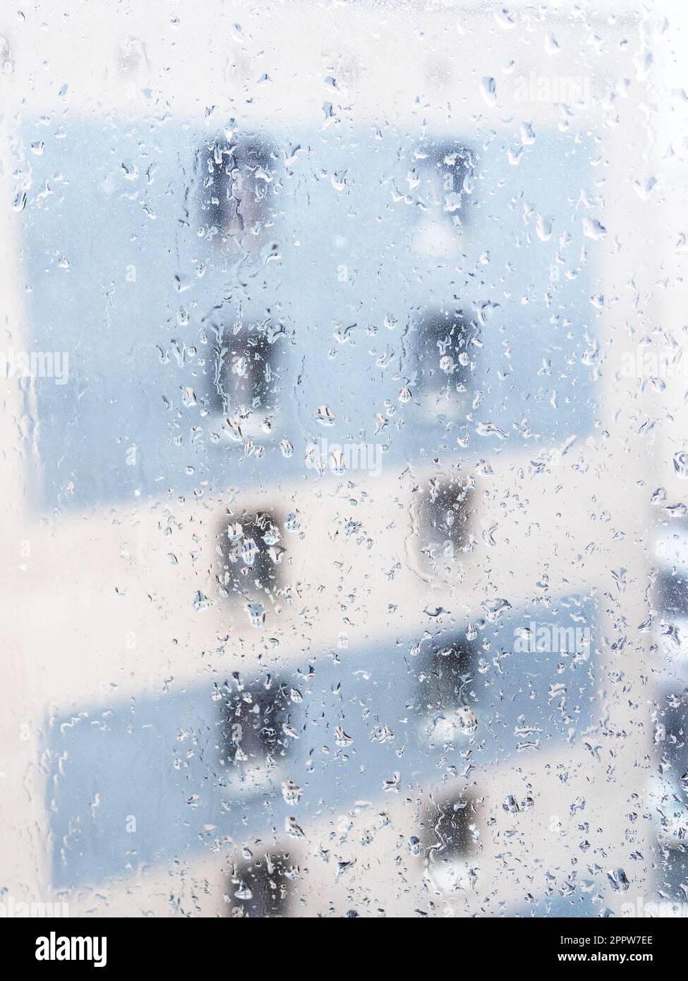rain drops on surface of window glass in city apartment and view of ...