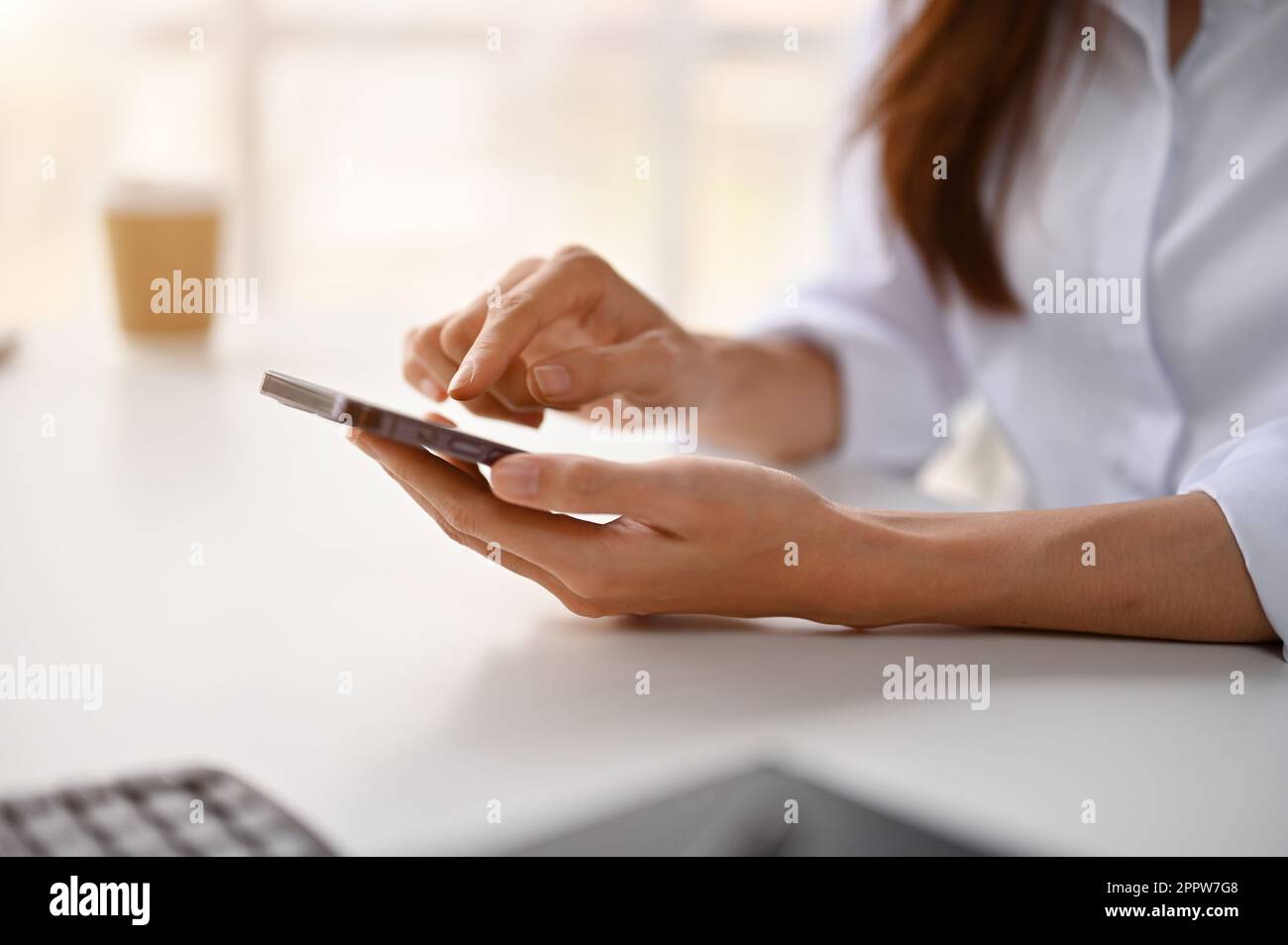 Close-up image of a female using her smartphone on a table. chatting ...