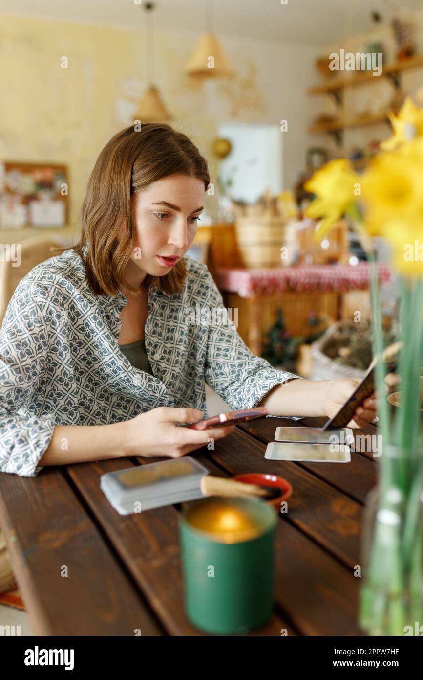 Beautiful young woman is guessing on cards with tarot, runes on wooden ...
