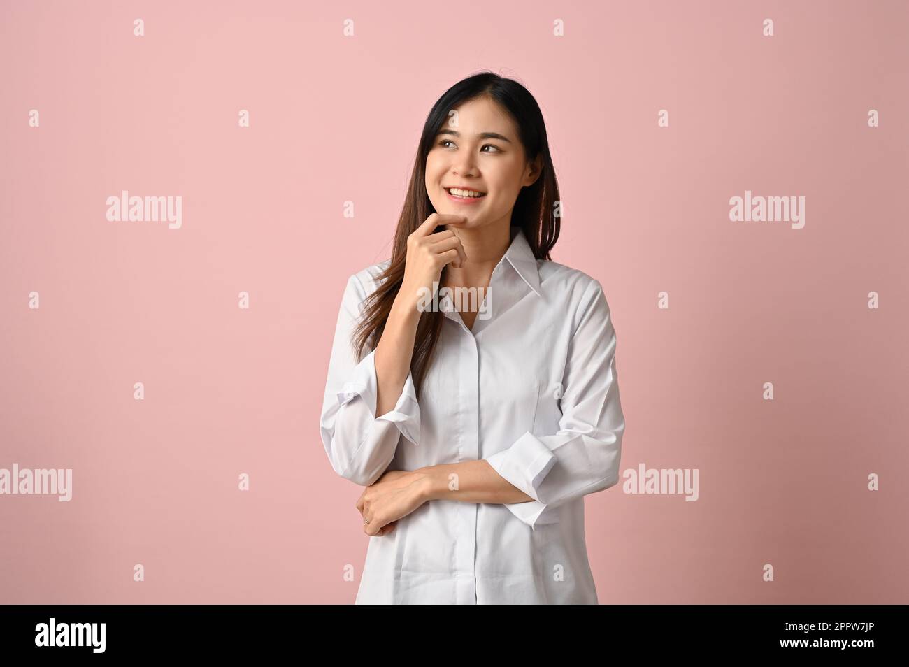 Wise and inspired millennial Asian woman in a white shirt hand on chin ...