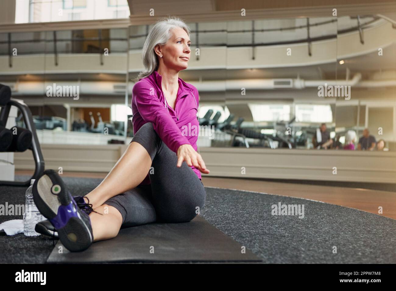 Stretching out all her muscles. a mature woman working out at the gym ...