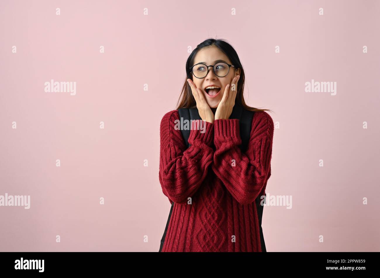 Excited and surprised young Asian female college student in a red ...