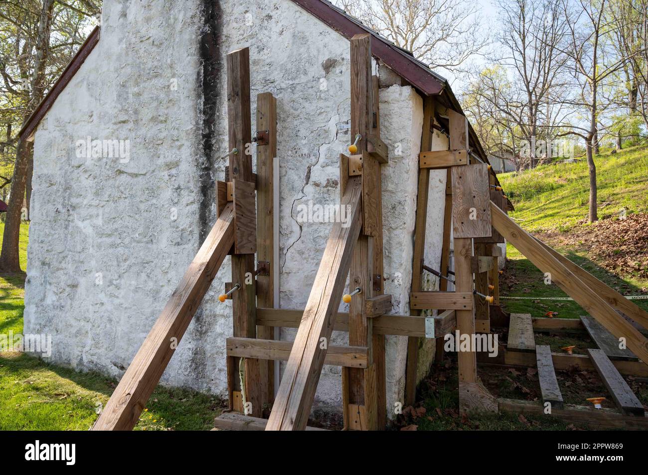 Wooden support scaffolding braces cracked wall of colonial cottage ...