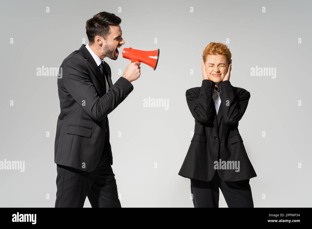 redhead manager with closed eyes covering ears with hands near boss ...