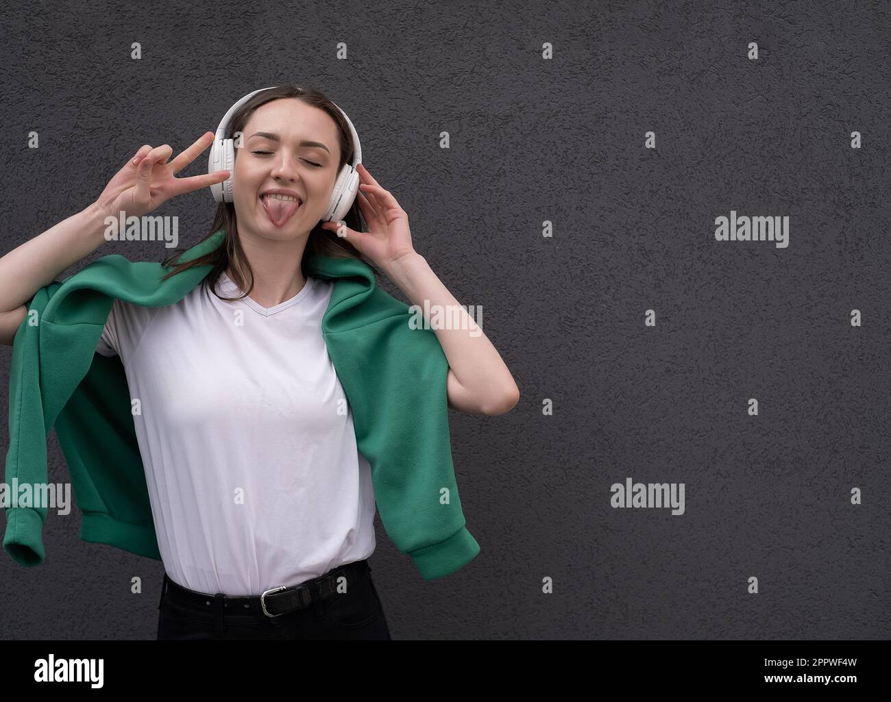 Emotional girl listens to music in headphones on a gray background ...